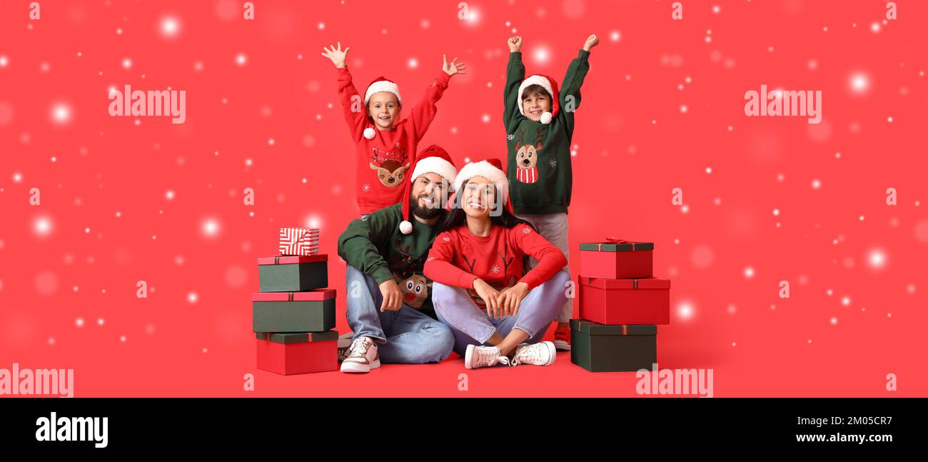 Happy family in Santa hats and with Christmas gifts on red background ...