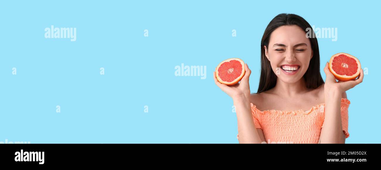 Funny young woman with fresh cut grapefruit on light blue background ...