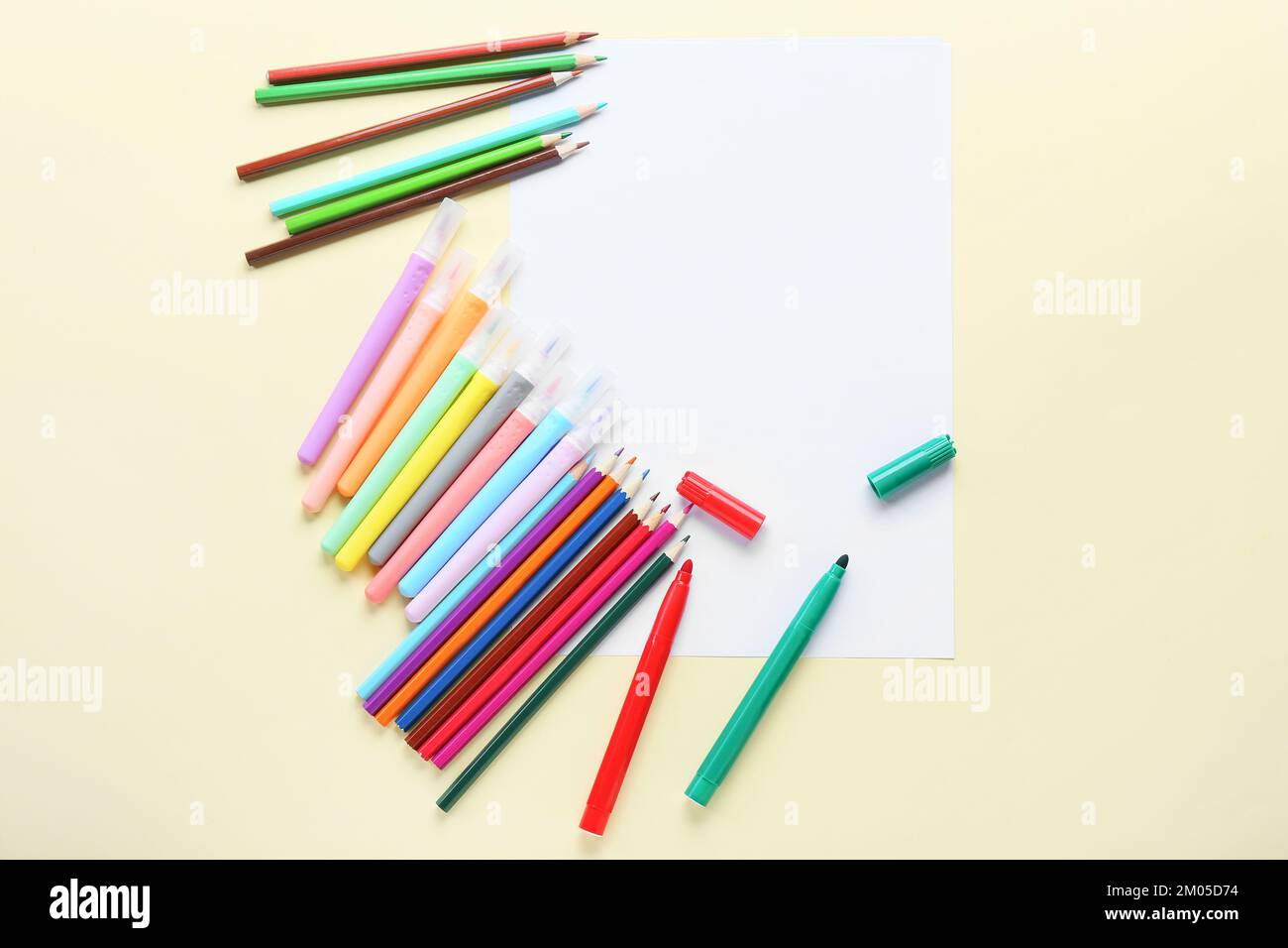 Blank paper sheet with pencils and felt-tip pens on beige background ...