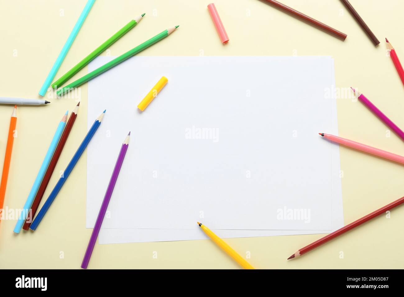 Blank paper sheet with pencils and felt-tip pens on beige background ...