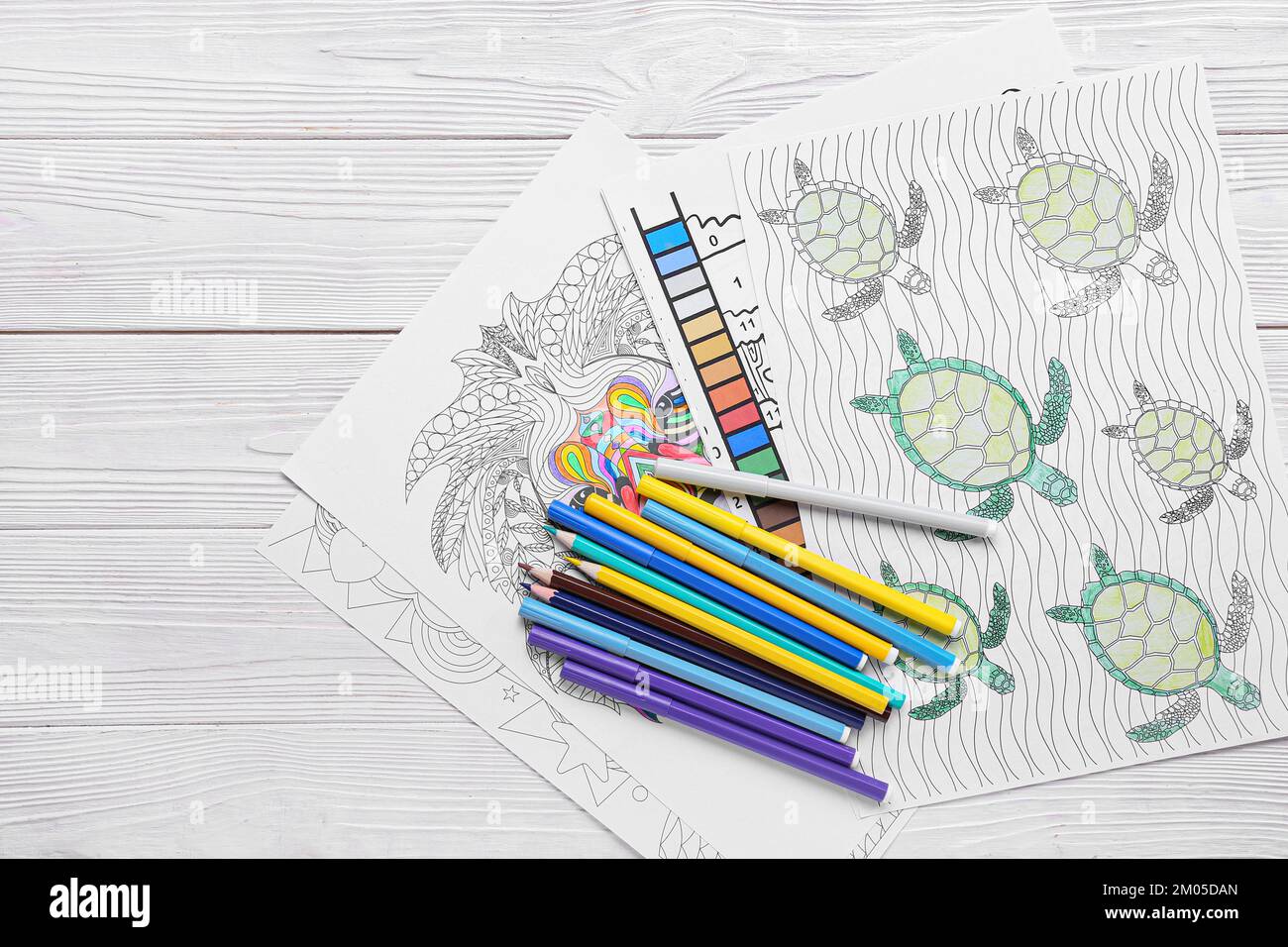 Coloring pages, felt-tip pens and pencils on white wooden background ...