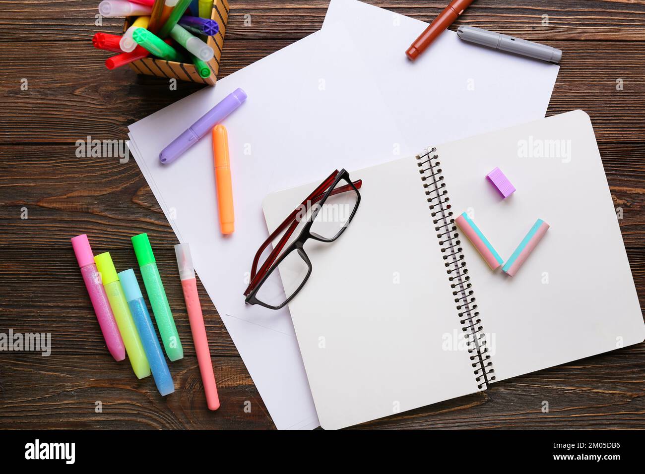 Paper sheets with notebook, felt-tip pens and eyeglasses on dark wooden ...