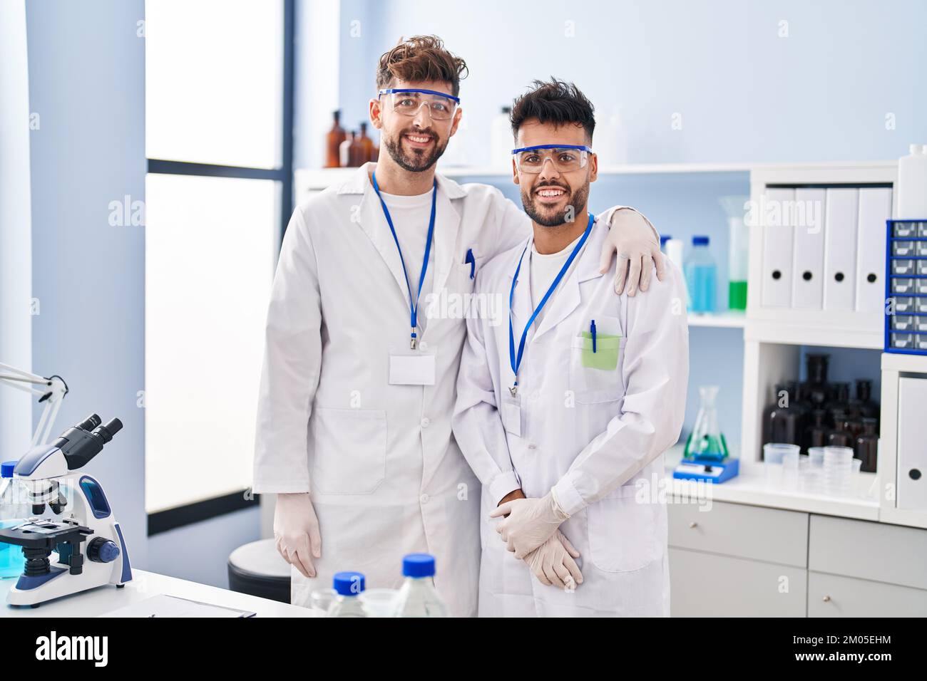 Young couple wearing scientist uniform hugging each other at laboratory ...