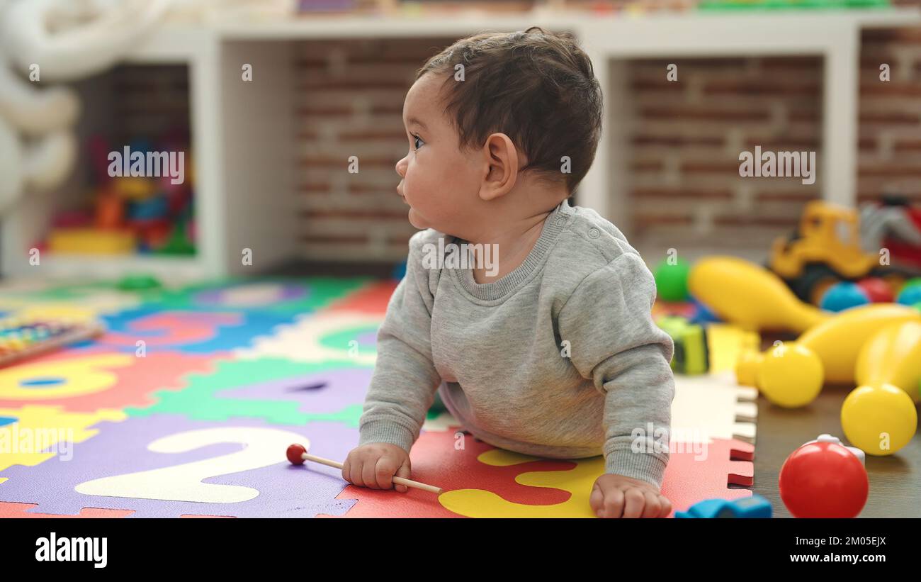 Adorable hispanic baby crawling on floor at kindergarten Stock Photo ...