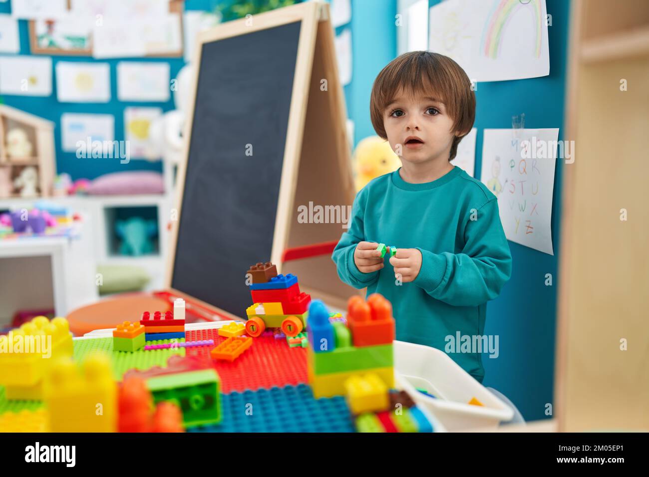 Adorable toddler playing with construction blocks standing at ...