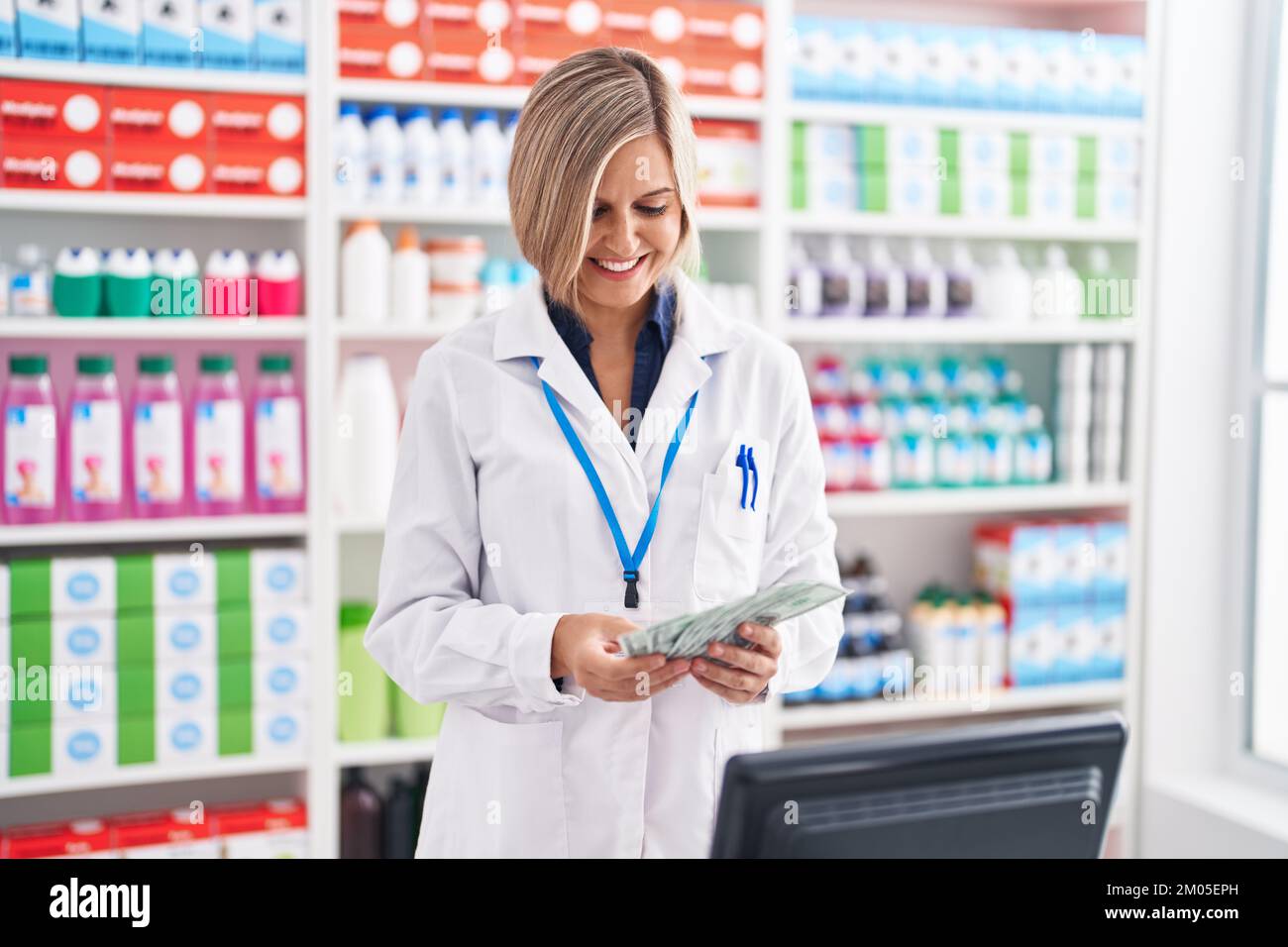 Young blonde woman pharmacist smiling confident counting dollars at ...