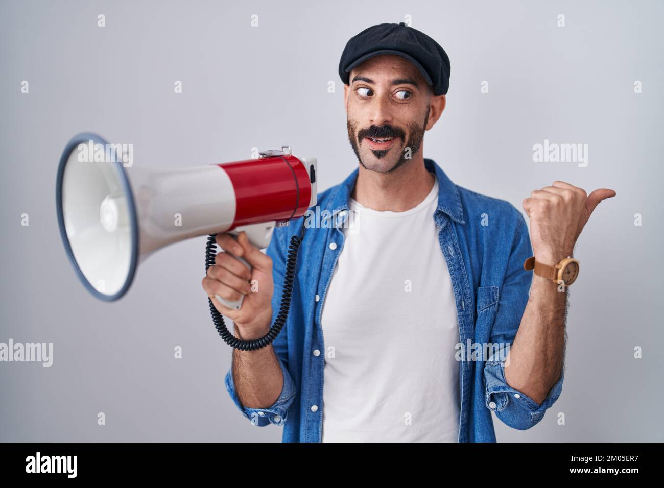 Hispanic man with beard shouting through megaphone pointing thumb up to ...
