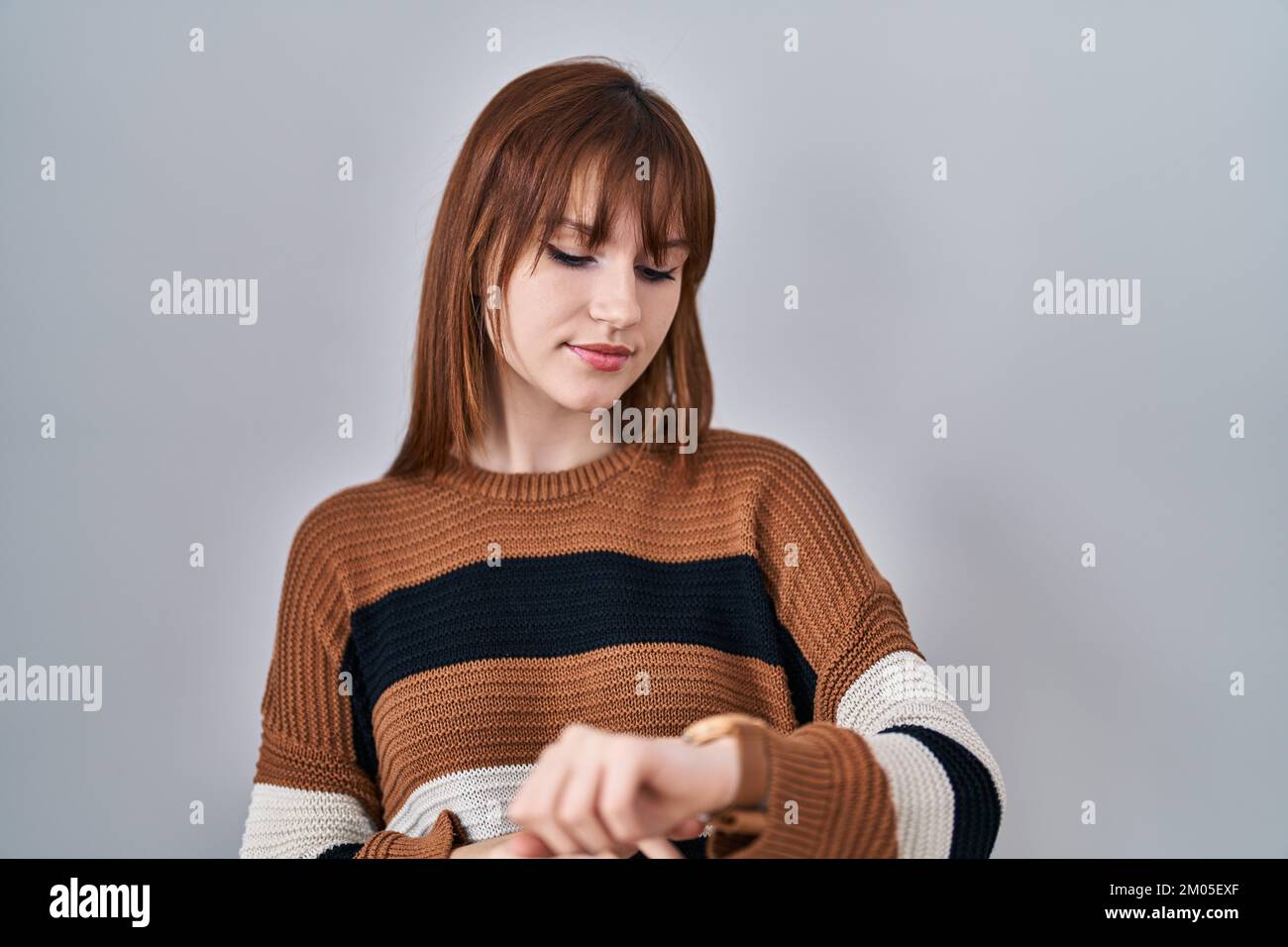 Young beautiful woman wearing striped sweater over isolated background ...