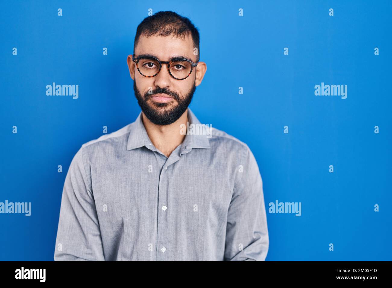 Middle east man with beard standing over blue background depressed and ...