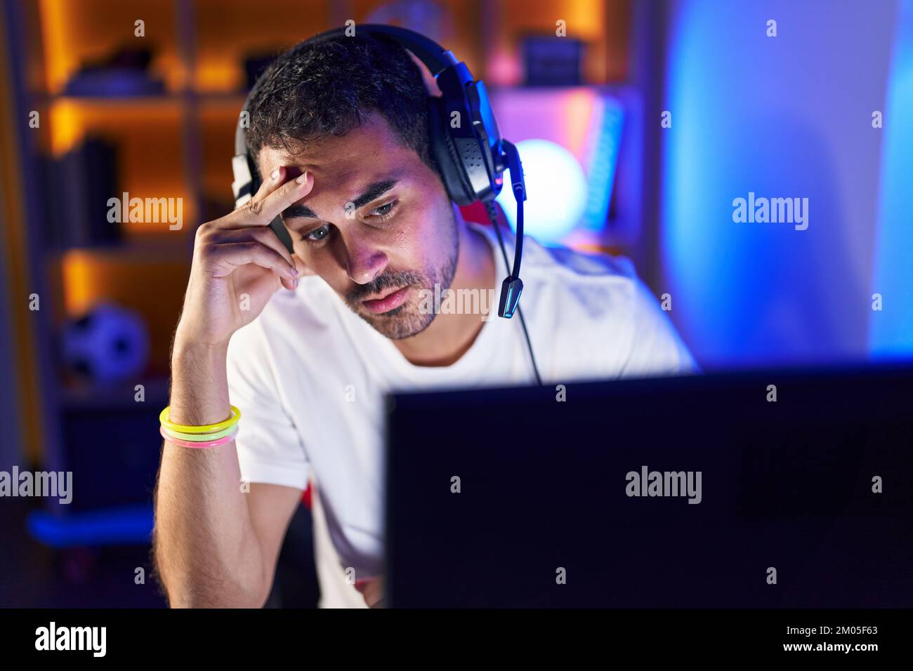 Young hispanic man streamer stressed using computer at gaming room ...