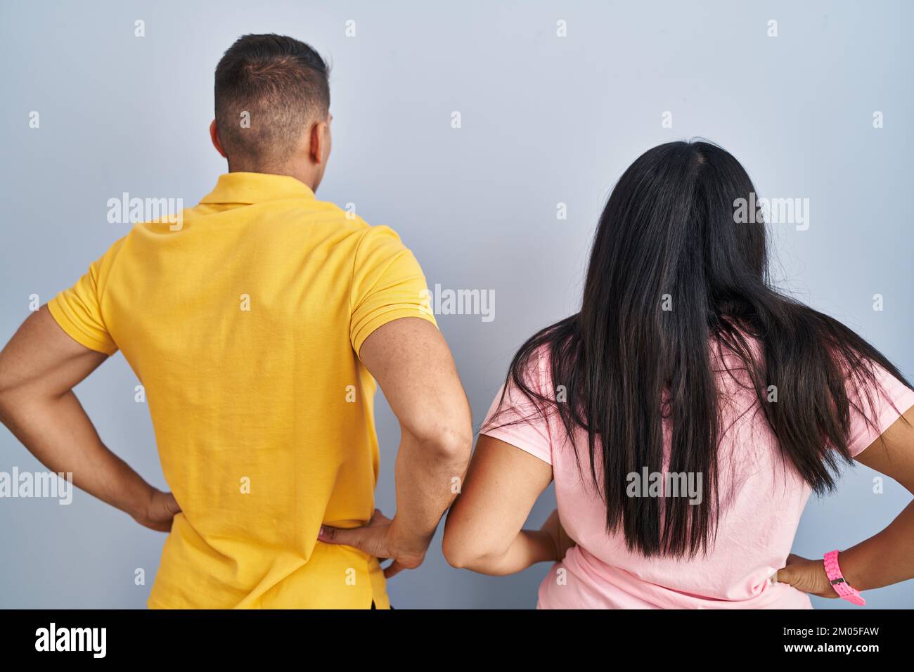 Young couple standing over isolated background standing backwards ...