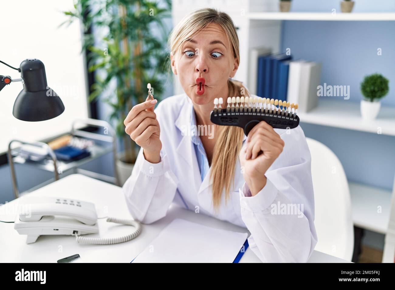 Beautiful dentist woman comparing teeth whitening making fish face with ...