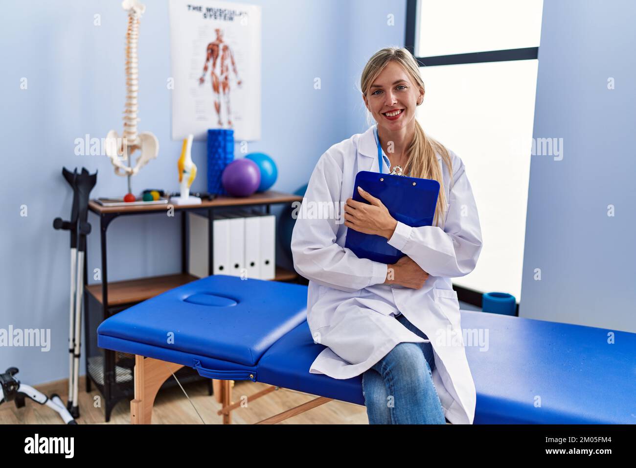 Young blonde woman wearing physiotherpist uniform holding checklist at ...
