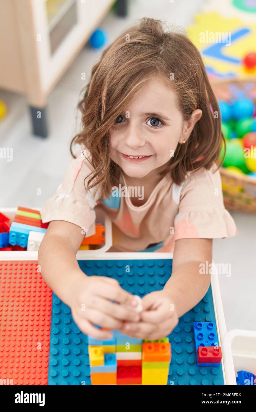 Adorable hispanic girl playing with construction blocks sitting on ...