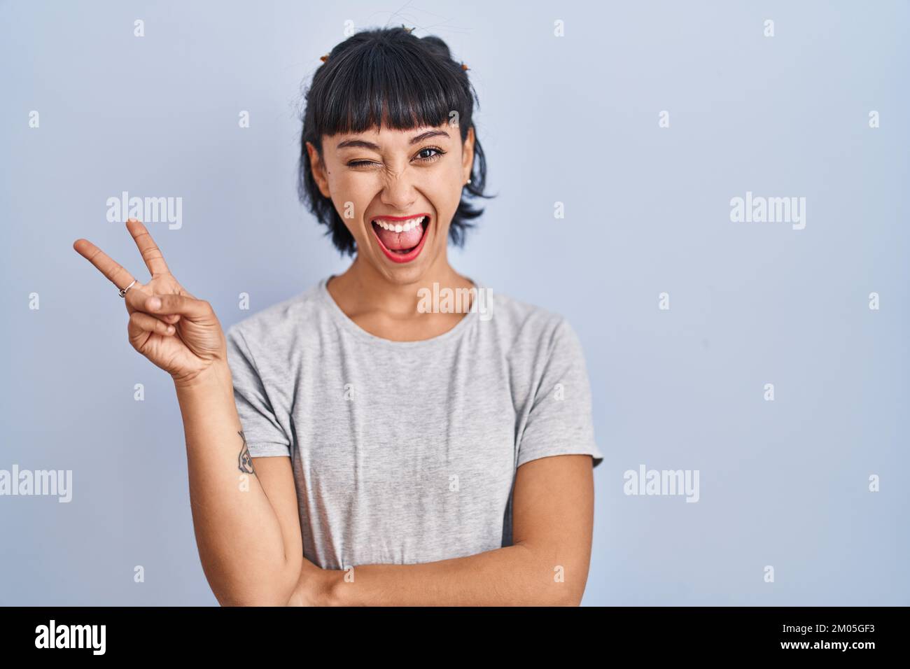 Young hispanic woman wearing casual t shirt over blue background ...
