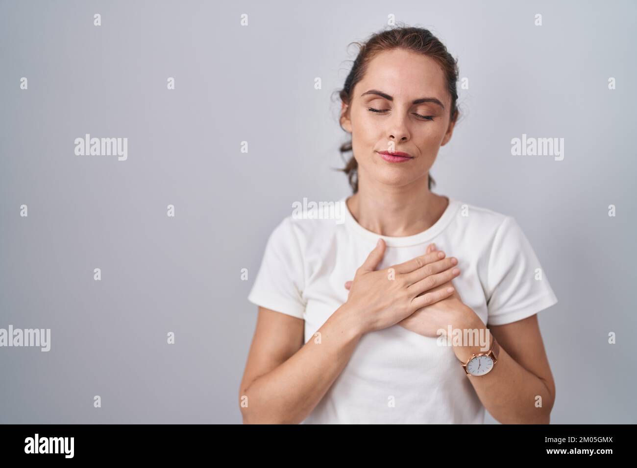 Beautiful brunette woman standing over isolated background smiling with ...