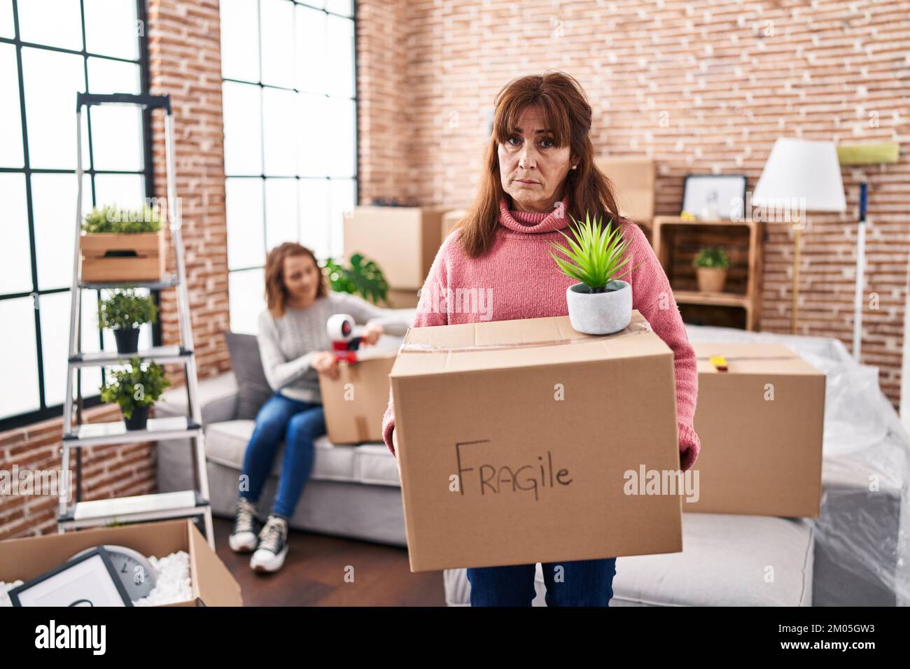 Mother and daughter moving to a new home holding cardboard box ...