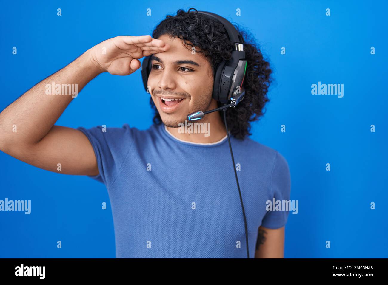 Hispanic man with curly hair listening to music using headphones very ...