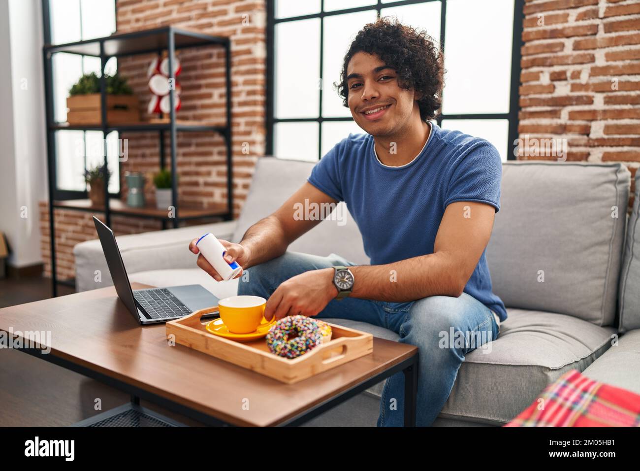 Young hispanic man using laptop having breakfast at home Stock Photo ...
