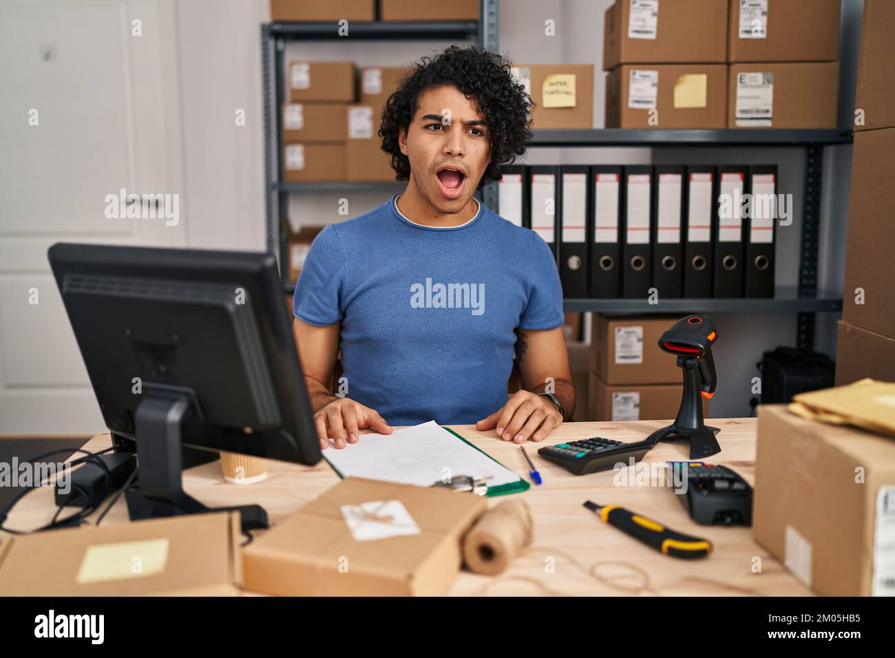 Hispanic man with curly hair working at small business ecommerce in ...