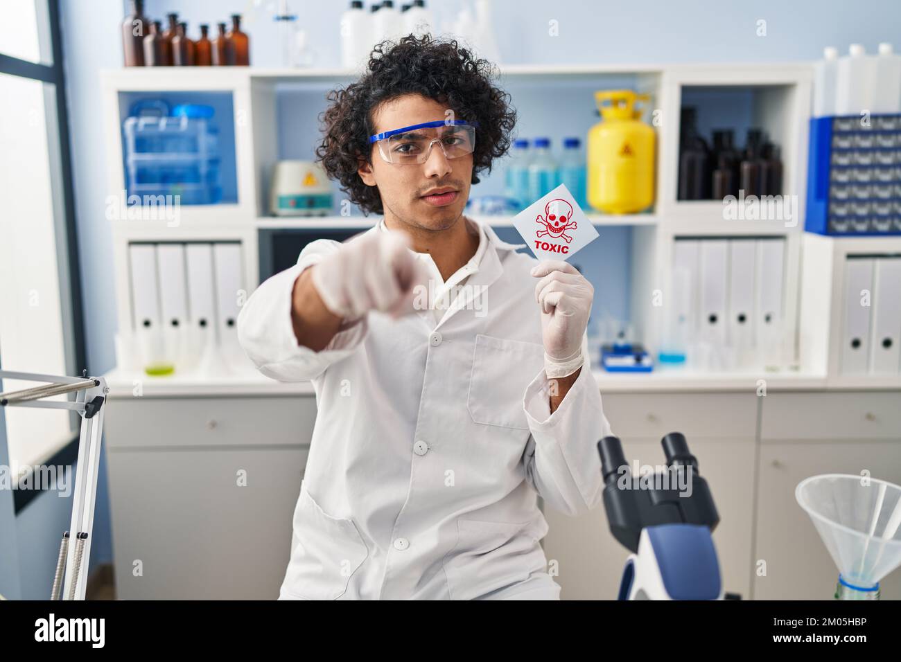 Hispanic man with curly hair working at scientist laboratory holding ...