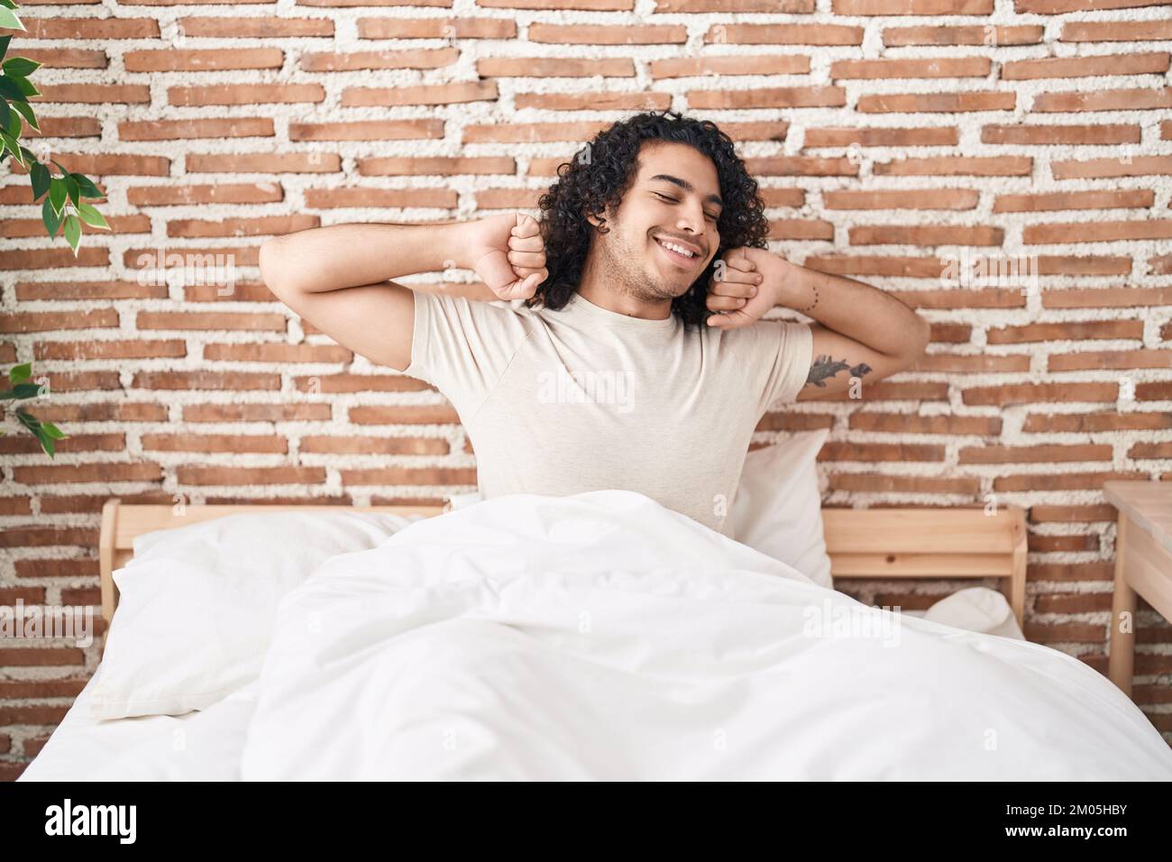 Young latin man waking up stretching arms at bedroom Stock Photo - Alamy