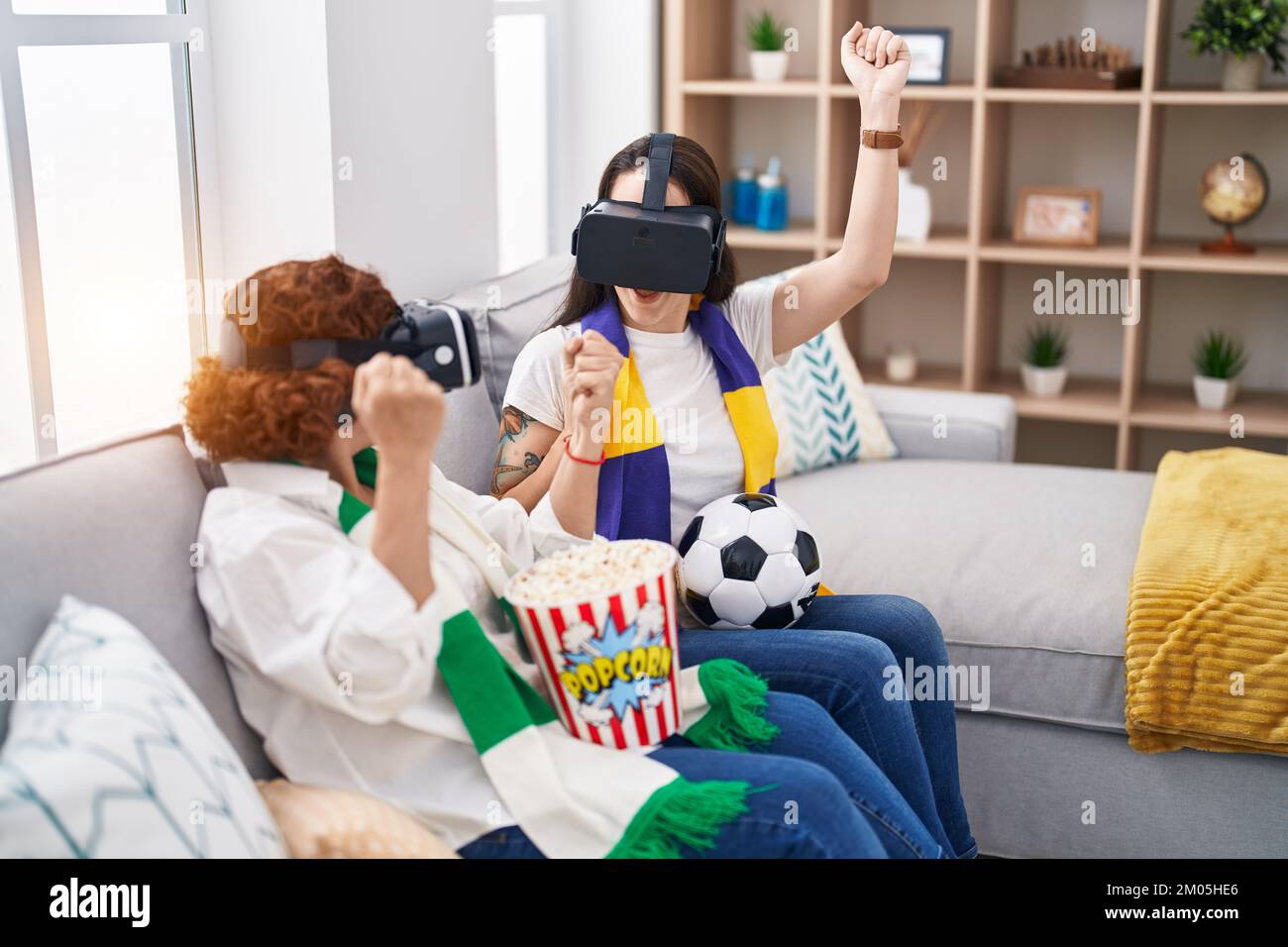 Two women mother and daughter watching soccer match using vr glasses at ...