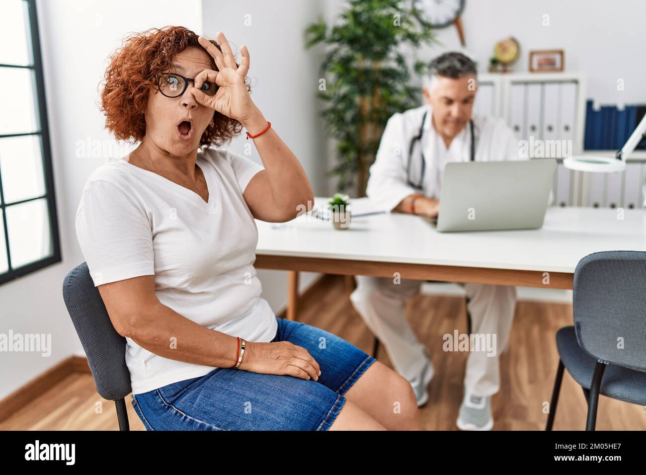 Senior woman sitting at doctor appointment doing ok gesture shocked ...