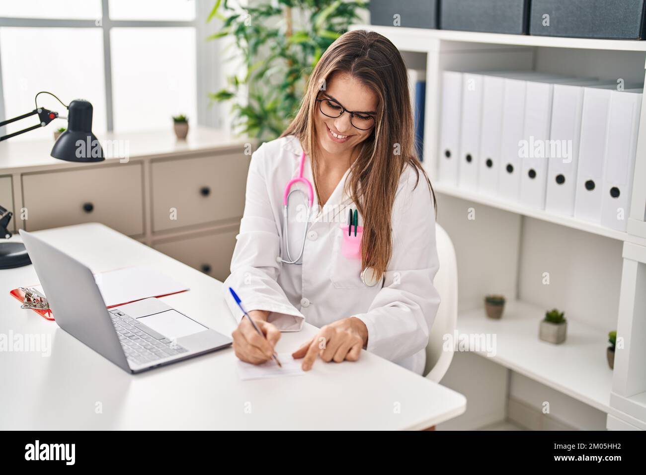 Young beautiful hispanic woman doctor using laptop writing on covid ...