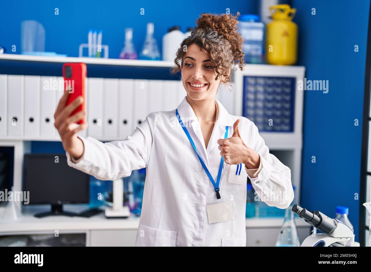 Hispanic woman with curly hair working at scientist laboratory doing ...