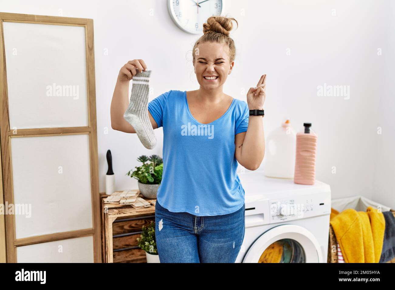 Young caucasian woman holding dirty sock at laundry room gesturing ...