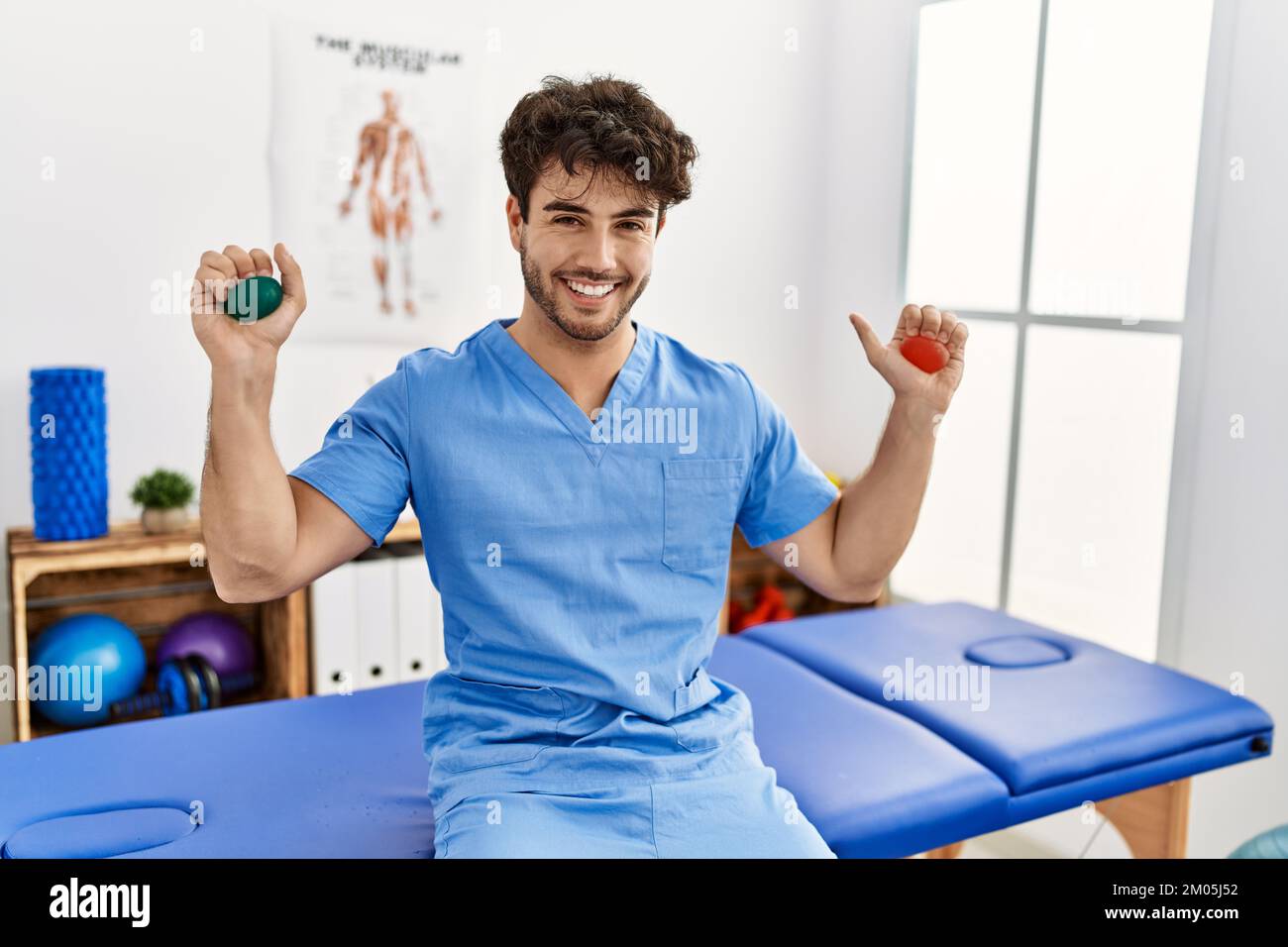 Young hispanic man wearing physio therapist uniform using anti stress ...