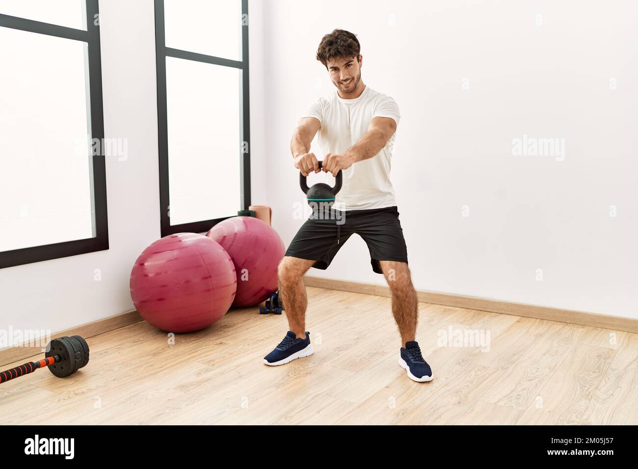 Young hispanic man smiling confident training with kettlebell at sport ...