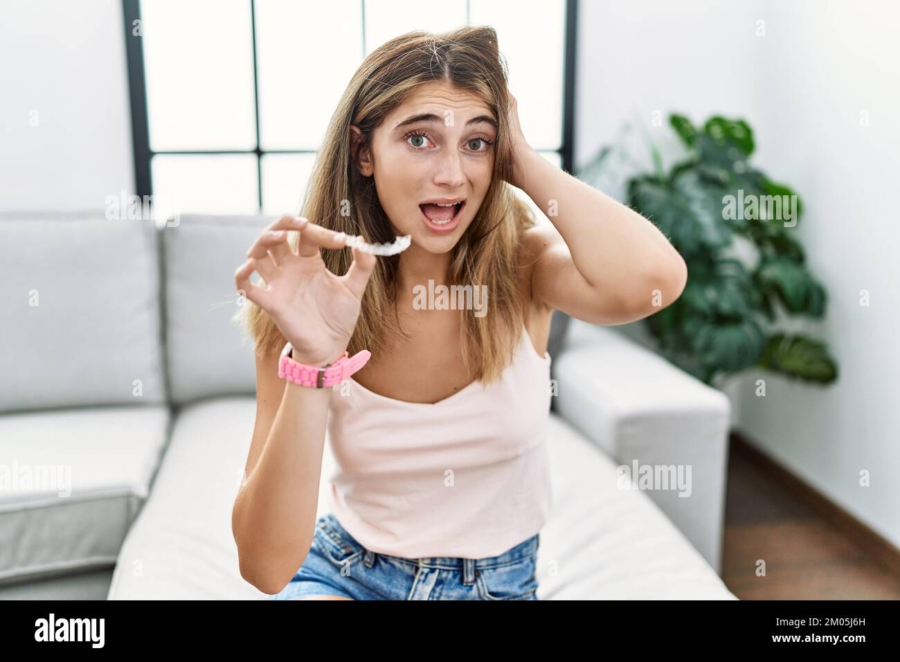Young blonde woman holding invisible aligner orthodontic crazy and ...