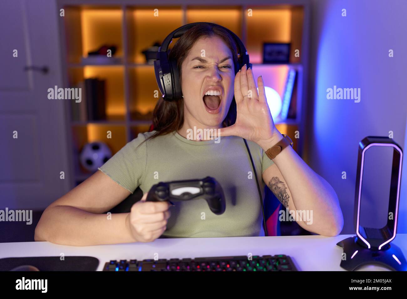 Beautiful brunette woman playing video games wearing headphones ...