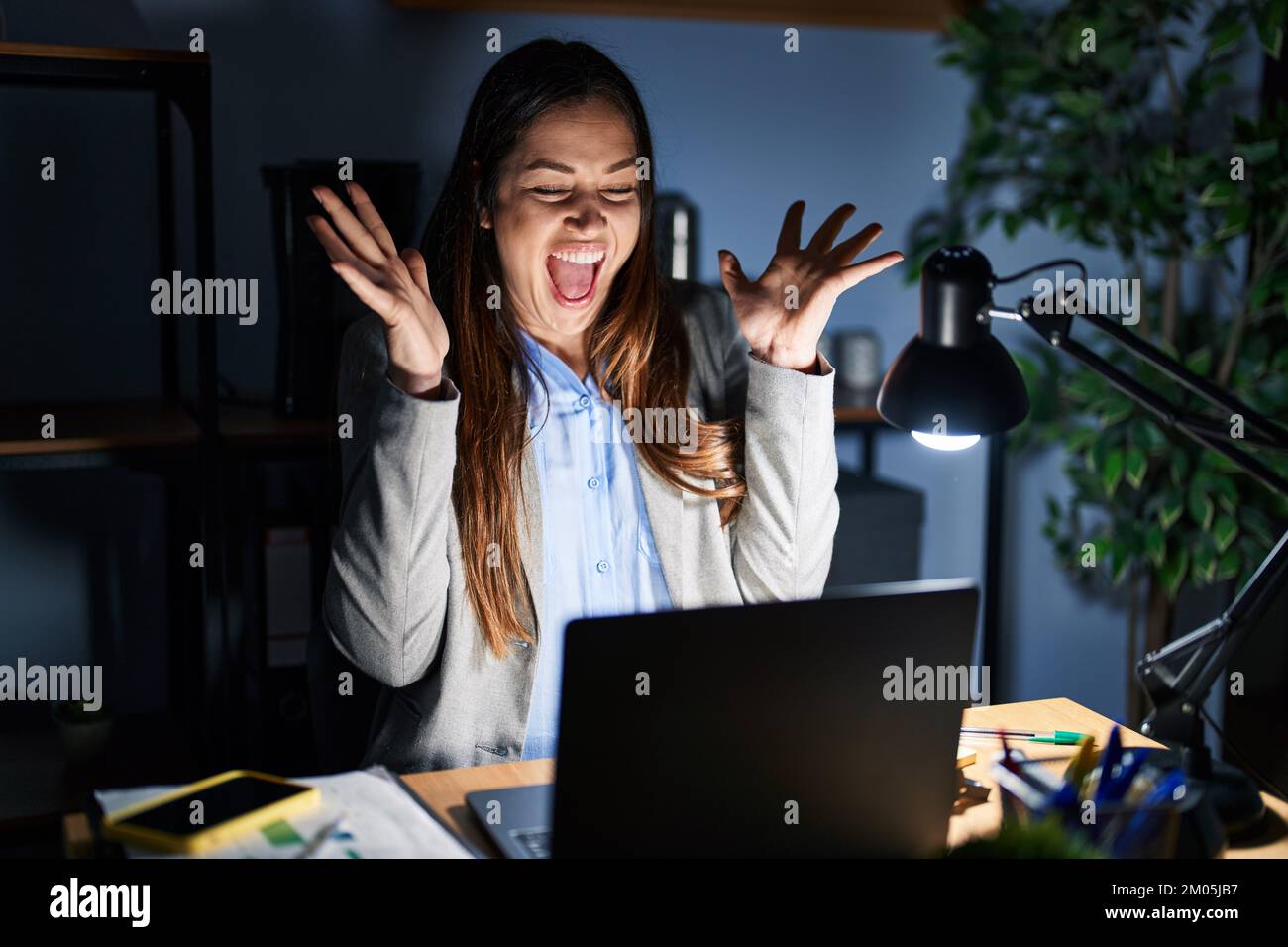 Young brunette woman working at the office at night celebrating crazy ...