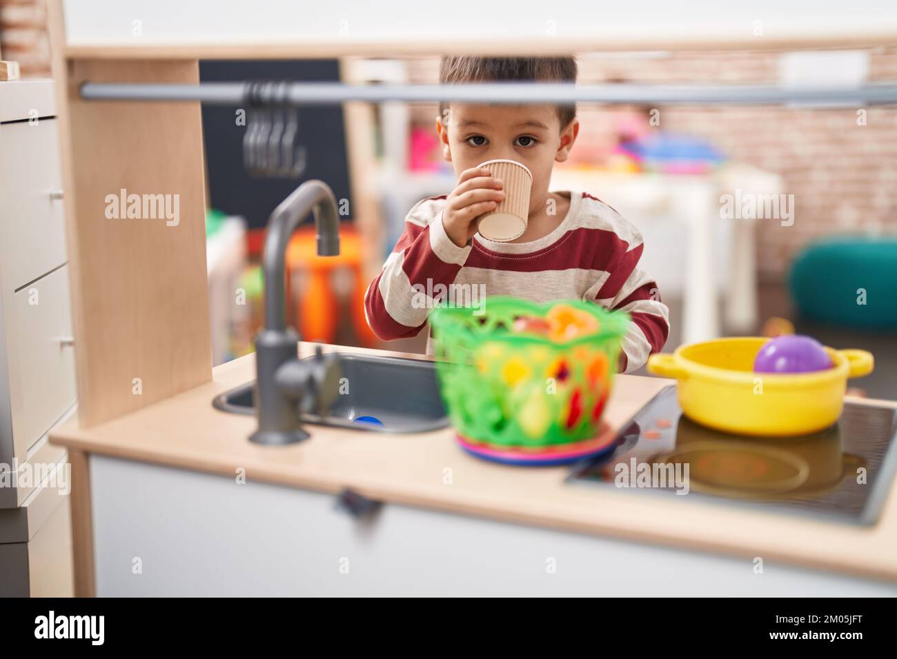 Adorable toddler playing with play kitchen standing at kindergarten ...