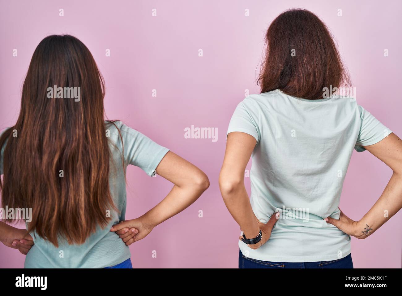 Young Mother And Daughter Standing Over Pink Background Standing