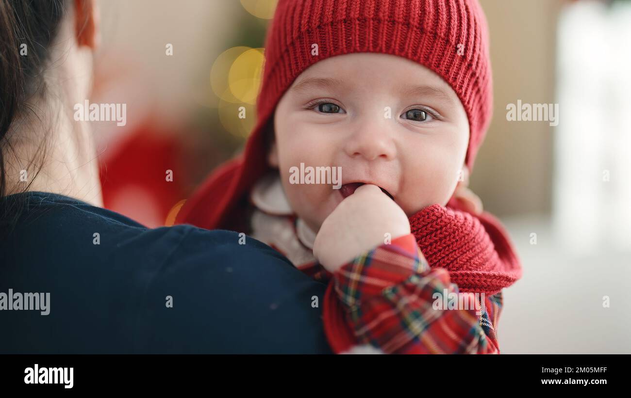 Adorable caucasian baby smiling confident relaxed on mother arms at ...