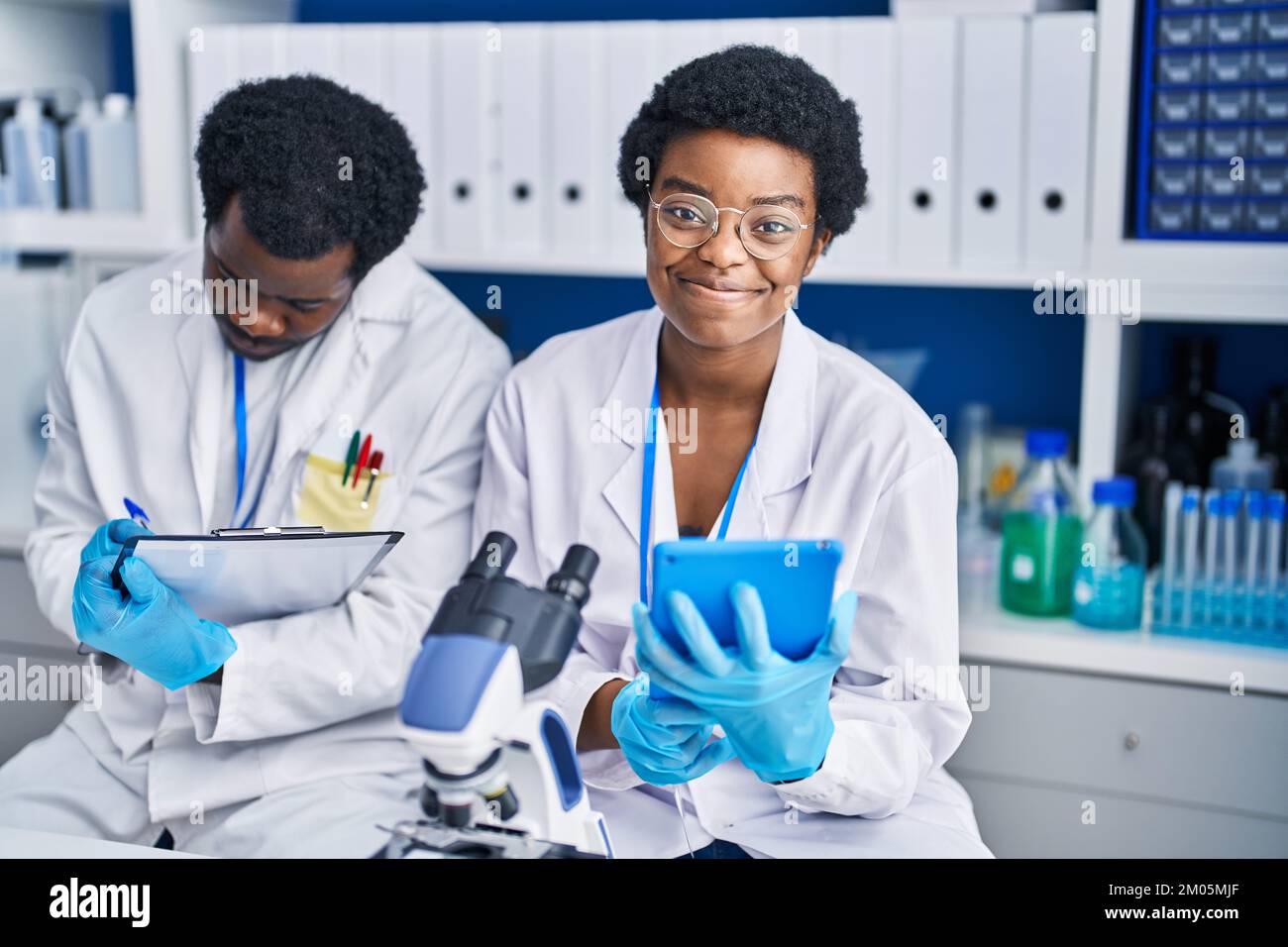 African american man and woman scientists using touchpad write on document at laboratory Stock ...