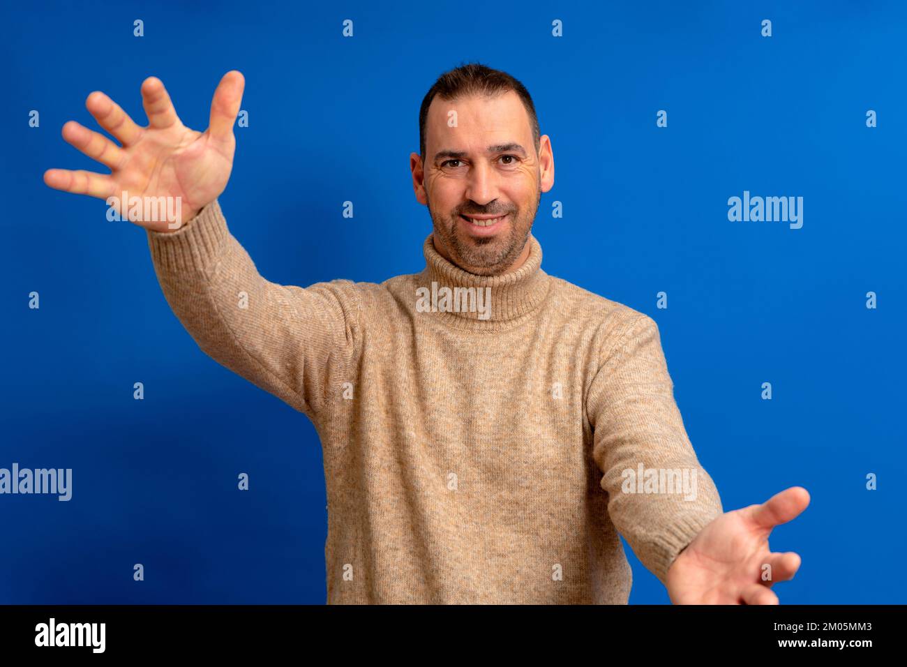 Happy handsome bearded hispanic man standing with arms raised, wants to ...