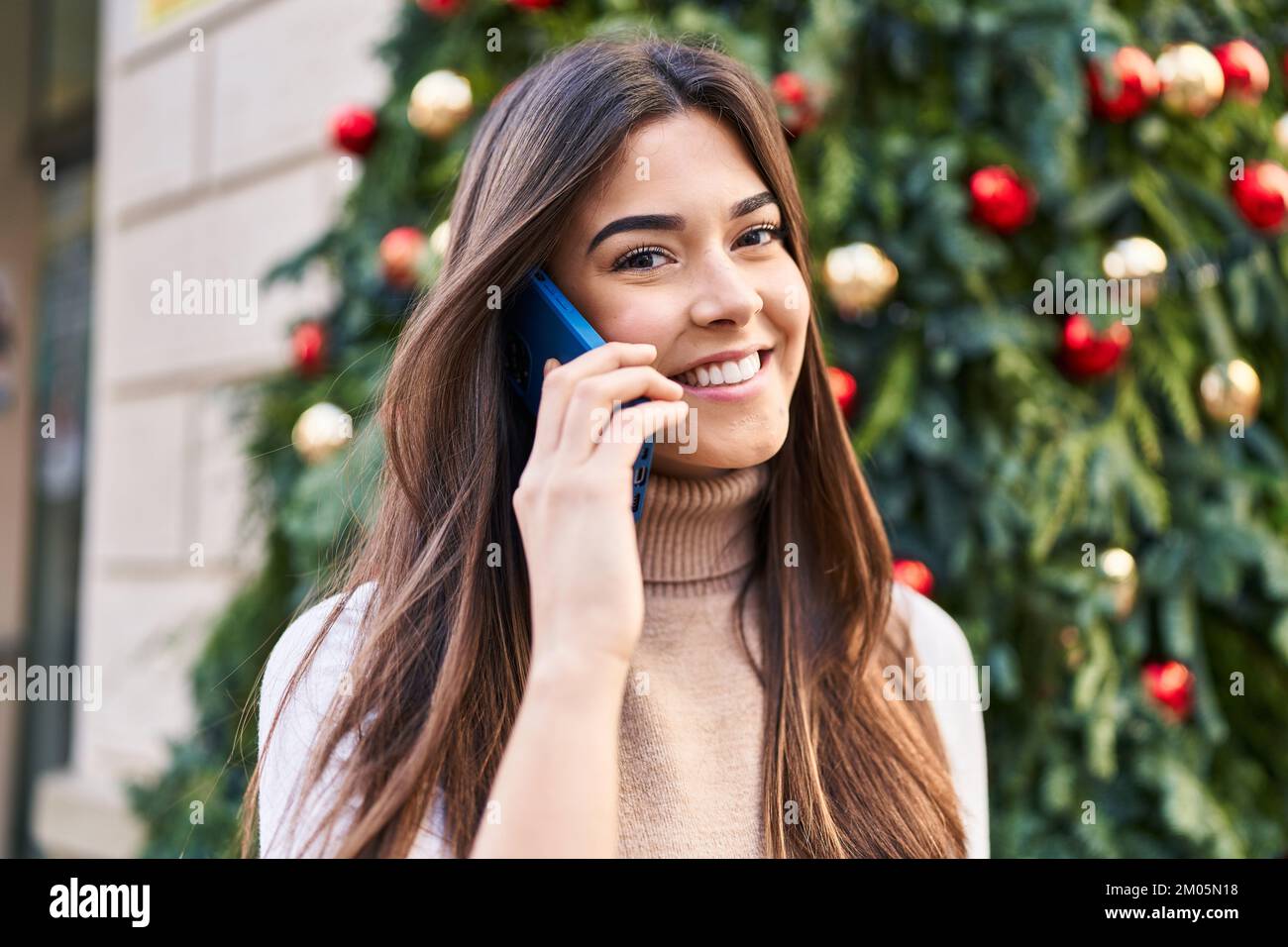 Young beautiful hispanic woman talking on smartphone standing by ...