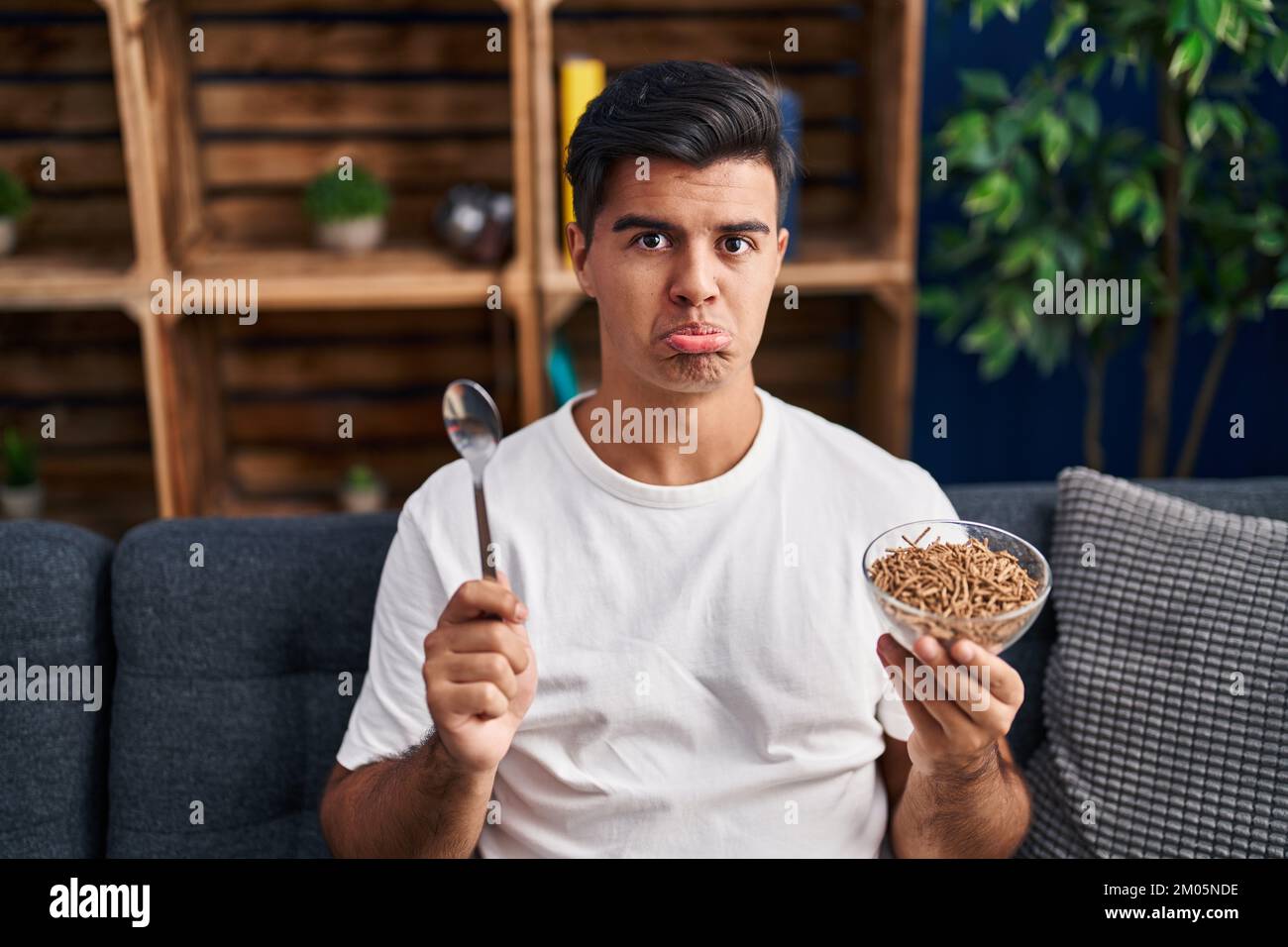 Hispanic man eating healthy whole grain cereals with spoon depressed ...