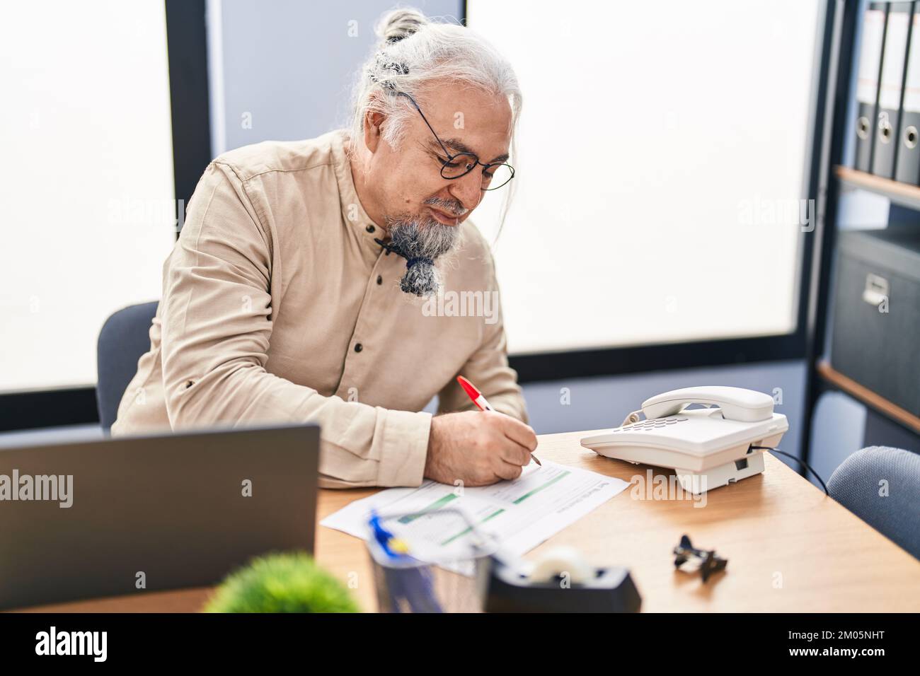 Middle age grey-haired man business worker using laptop writing on ...