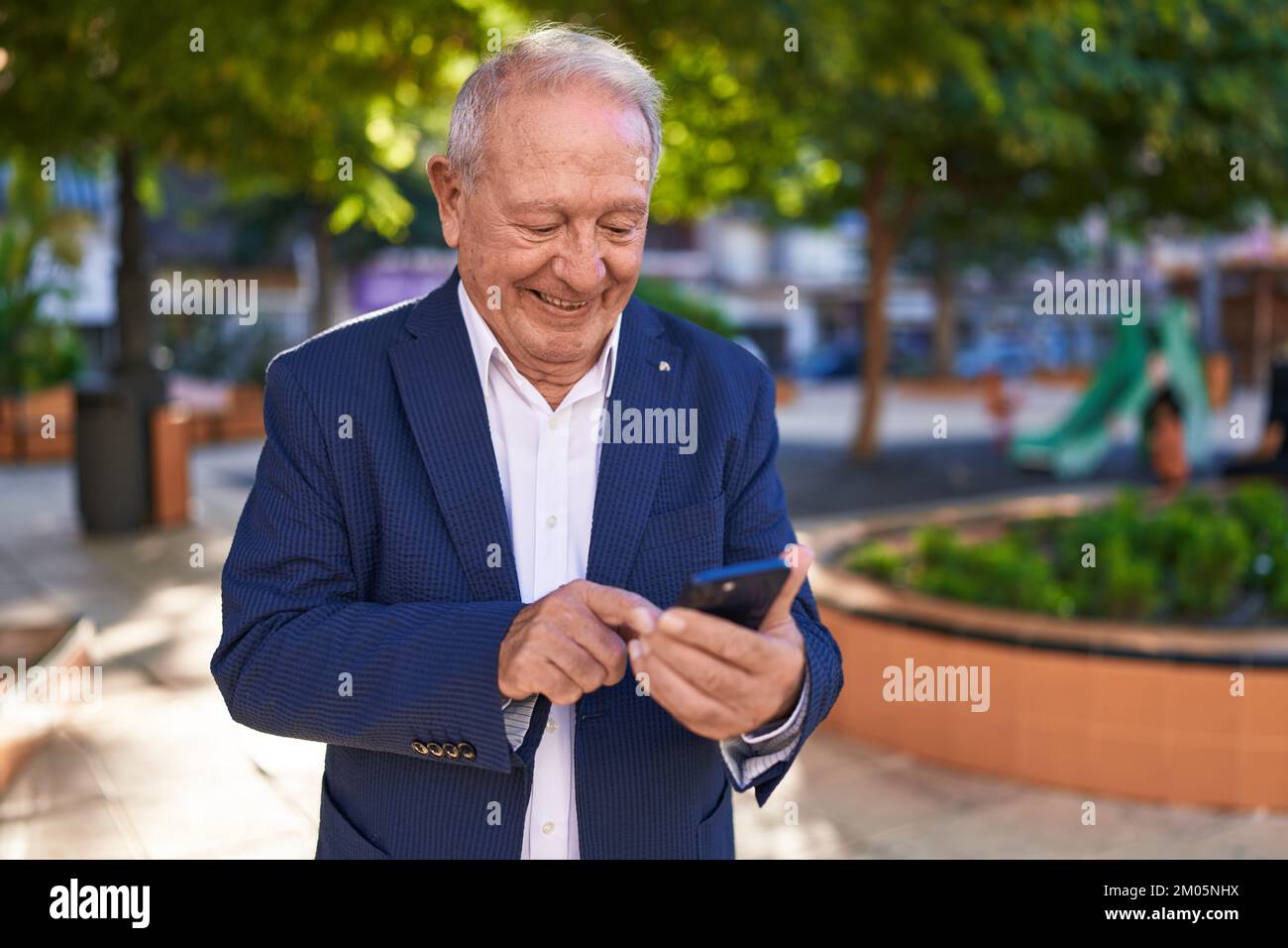 Middle age grey-haired man smiling confident using smartphone at park ...