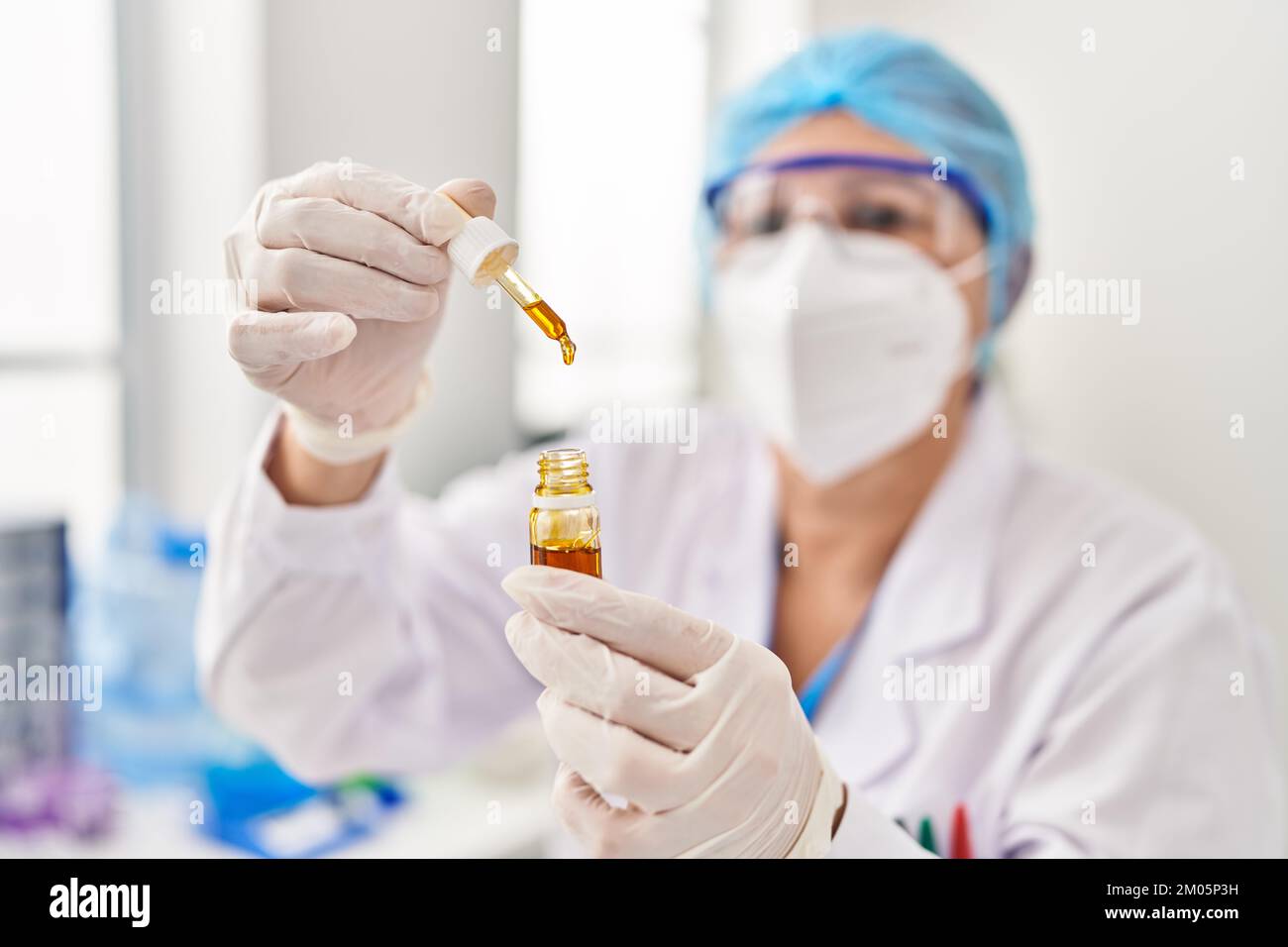 Middle age woman wearing scientist unifor and medical mask working at ...