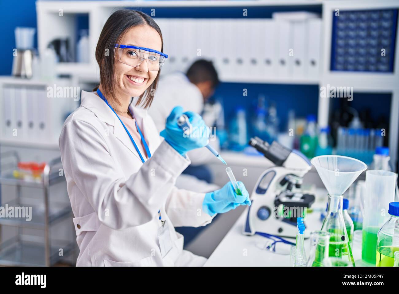 Man and woman scientists pouring liquid on test tube at laboratory ...