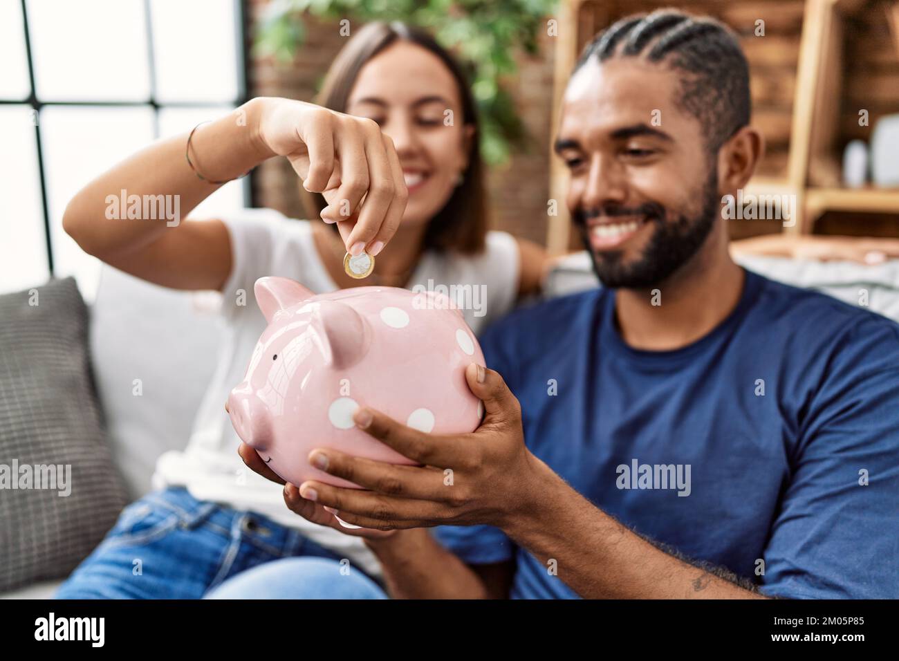 Man and woman couple smiling confident insert coin on piggy bank at ...