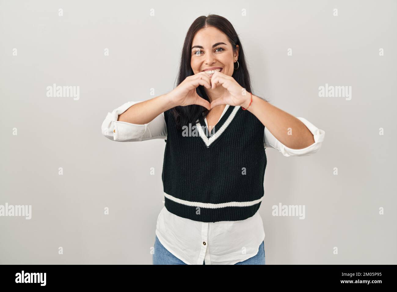 Young hispanic woman standing over isolated background smiling in love ...