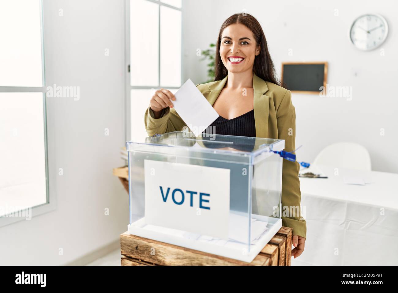 Young beautiful hispanic woman smiling confident putting vote on ballot ...
